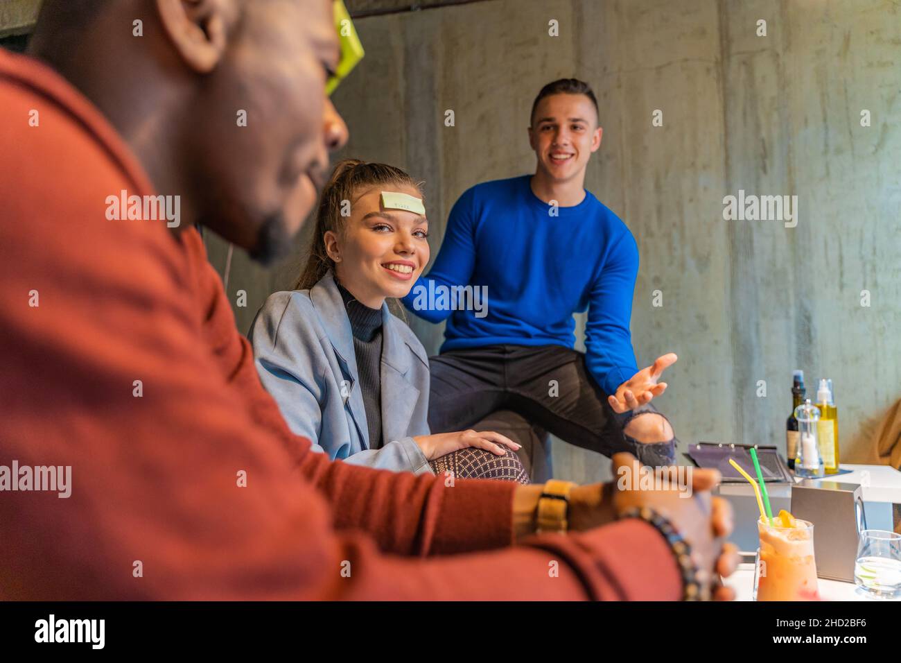 Beautiful and young friends are giving their friend hints for his word ...
