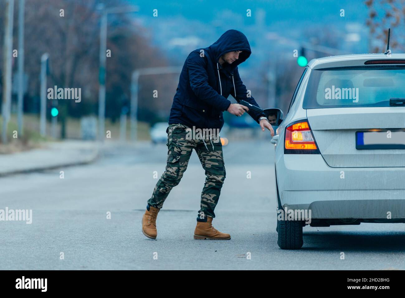 The car thief is pulling the car owner out of his car and trying to get ...