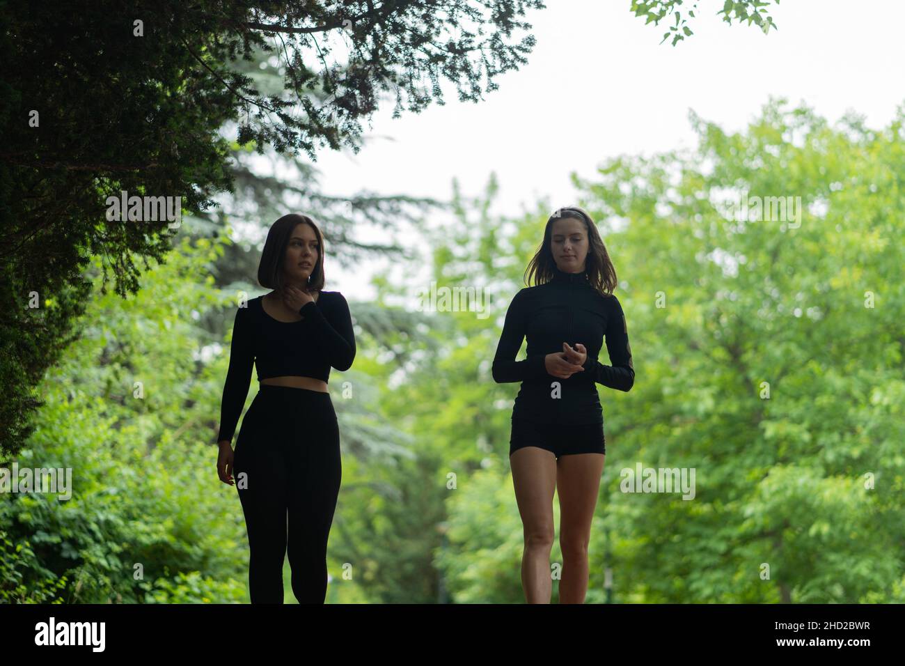 Two attractive girls are talking while walking on the running track ...