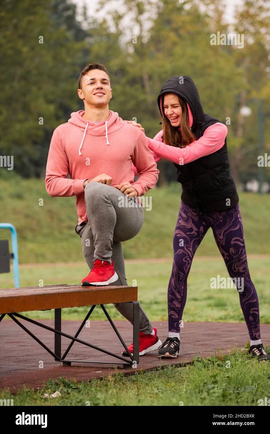 Attractive and amazing friends are stretching together on the bench ...