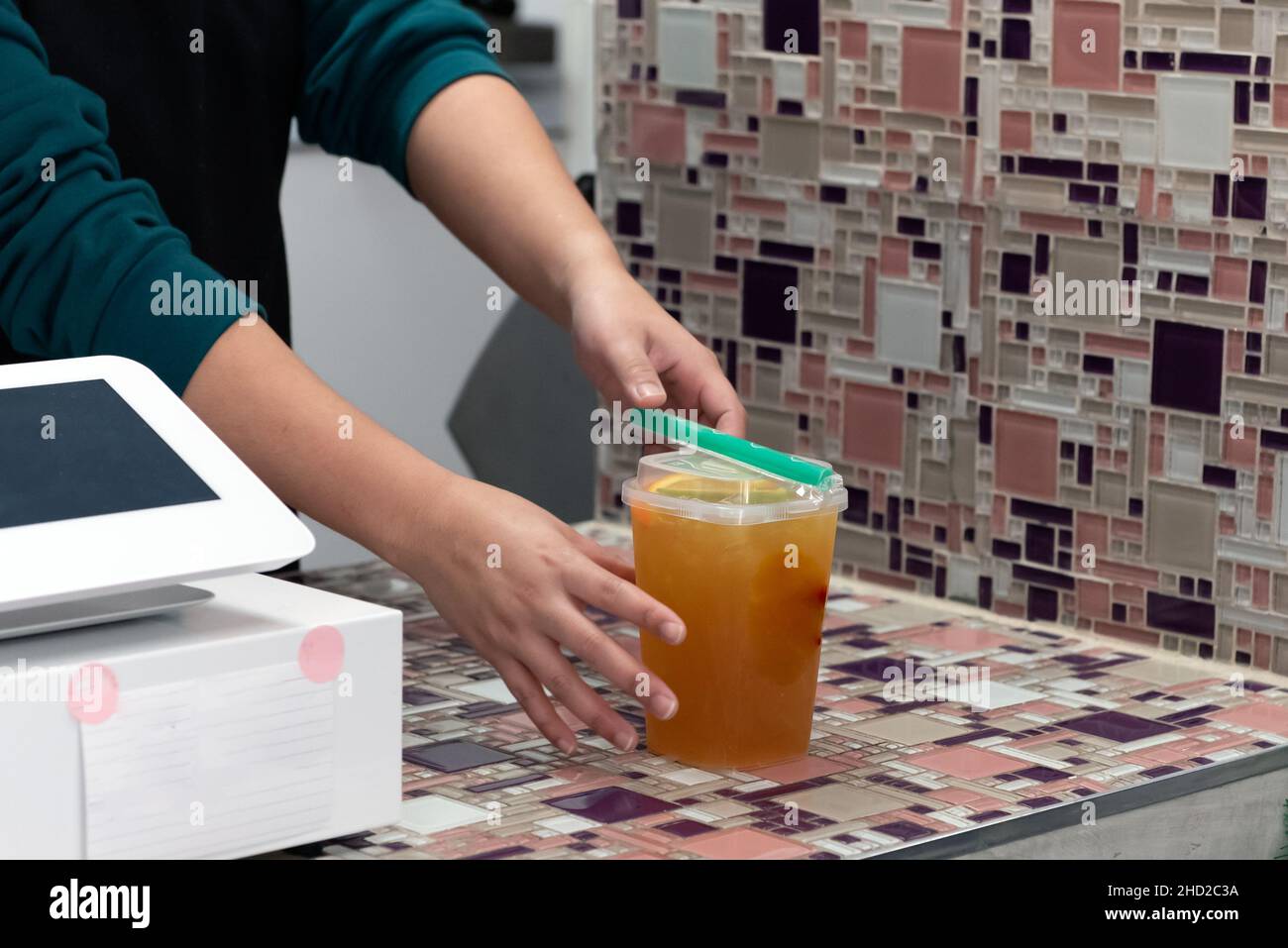 Hands serving the Iced Thai Tea Boba, with lid an d straw, across the ...