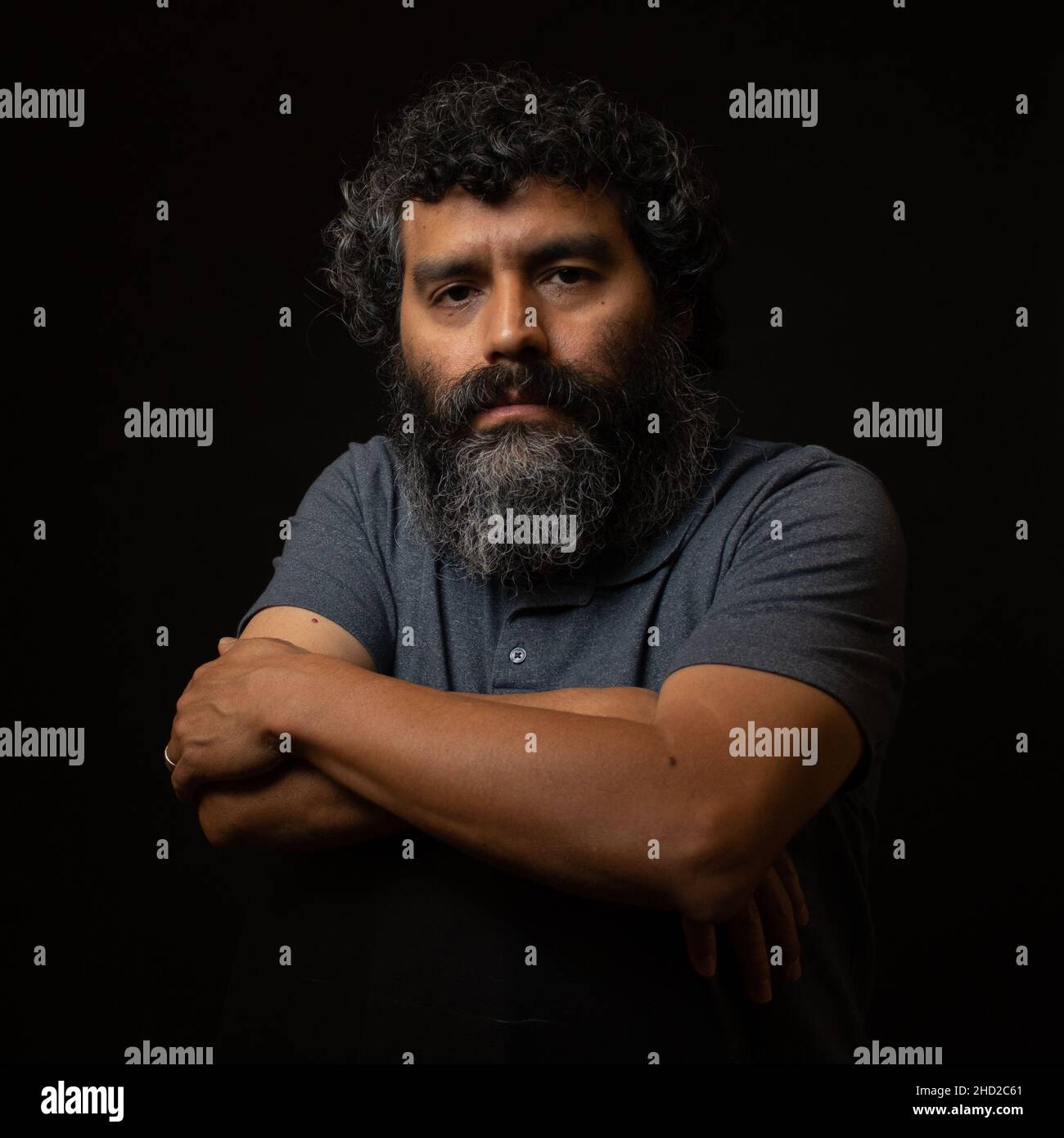 Portrait of a Hispanic male with facial hair posing on a black ...