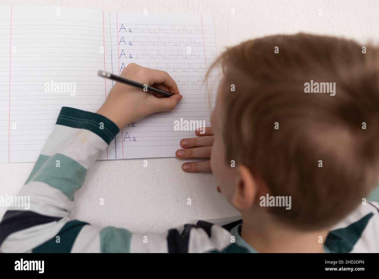 School boy practicing writing the alphabet at home. Boy child kid ...