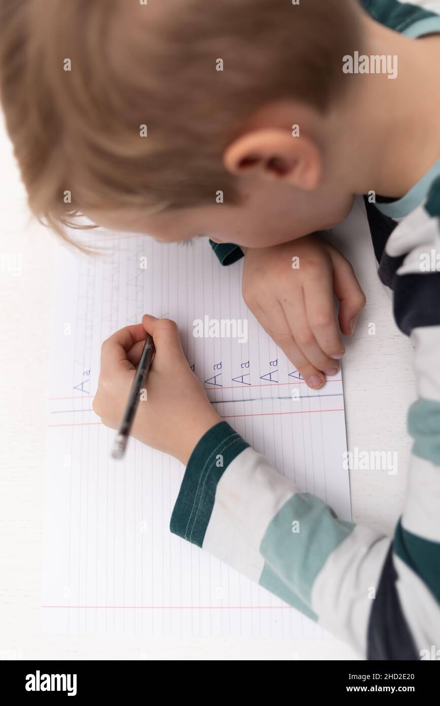 School boy practicing writing the alphabet at home. Boy child kid ...