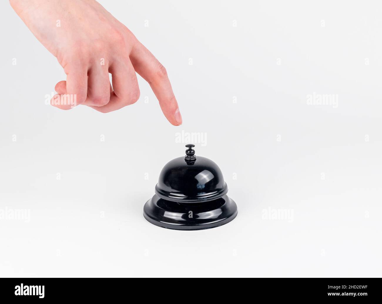 Desk bell is pressed by female hand. Concept image on white background ...