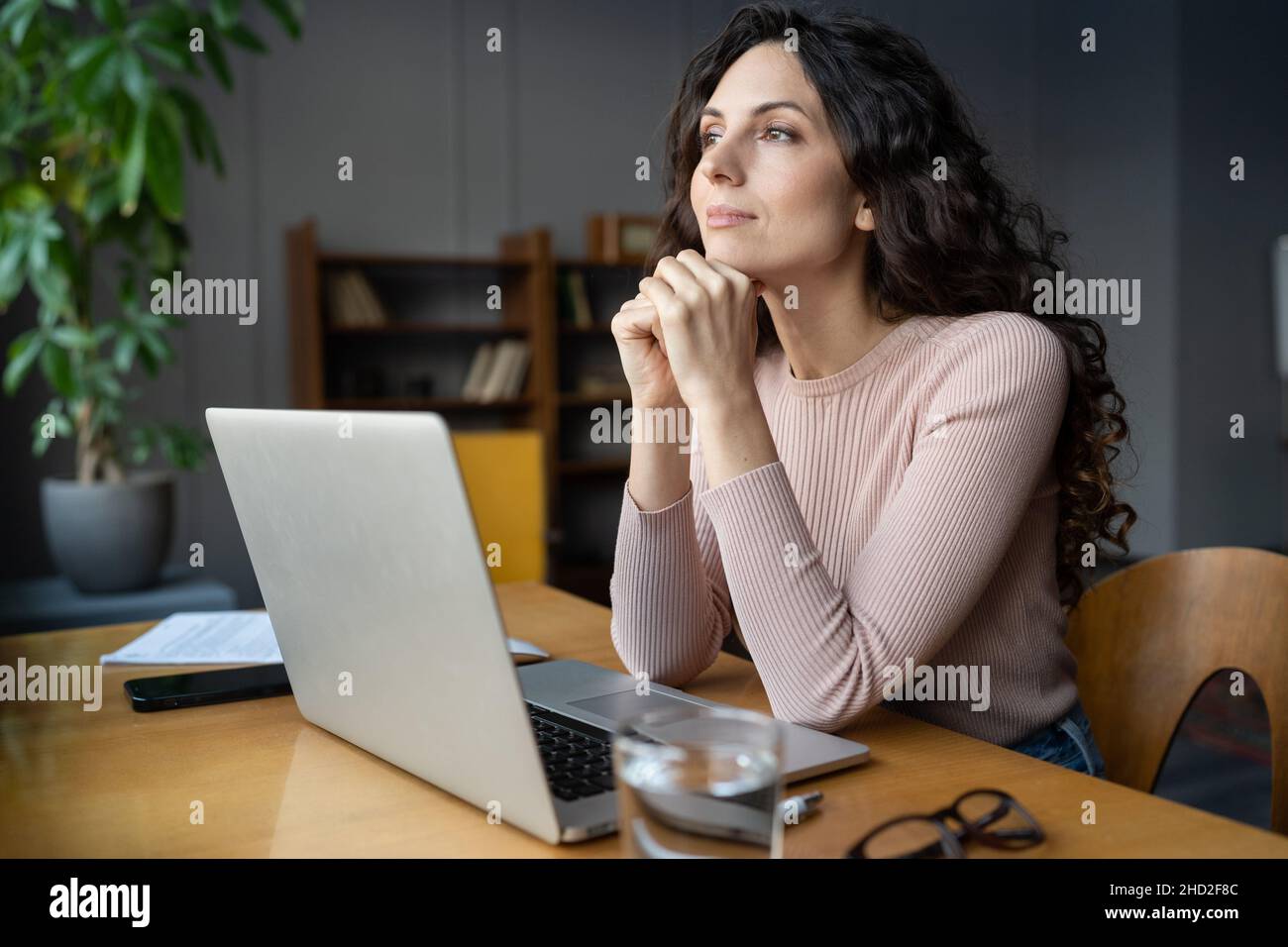 Dreamy businesswoman entrepreneur look in window distracted from laptop ...
