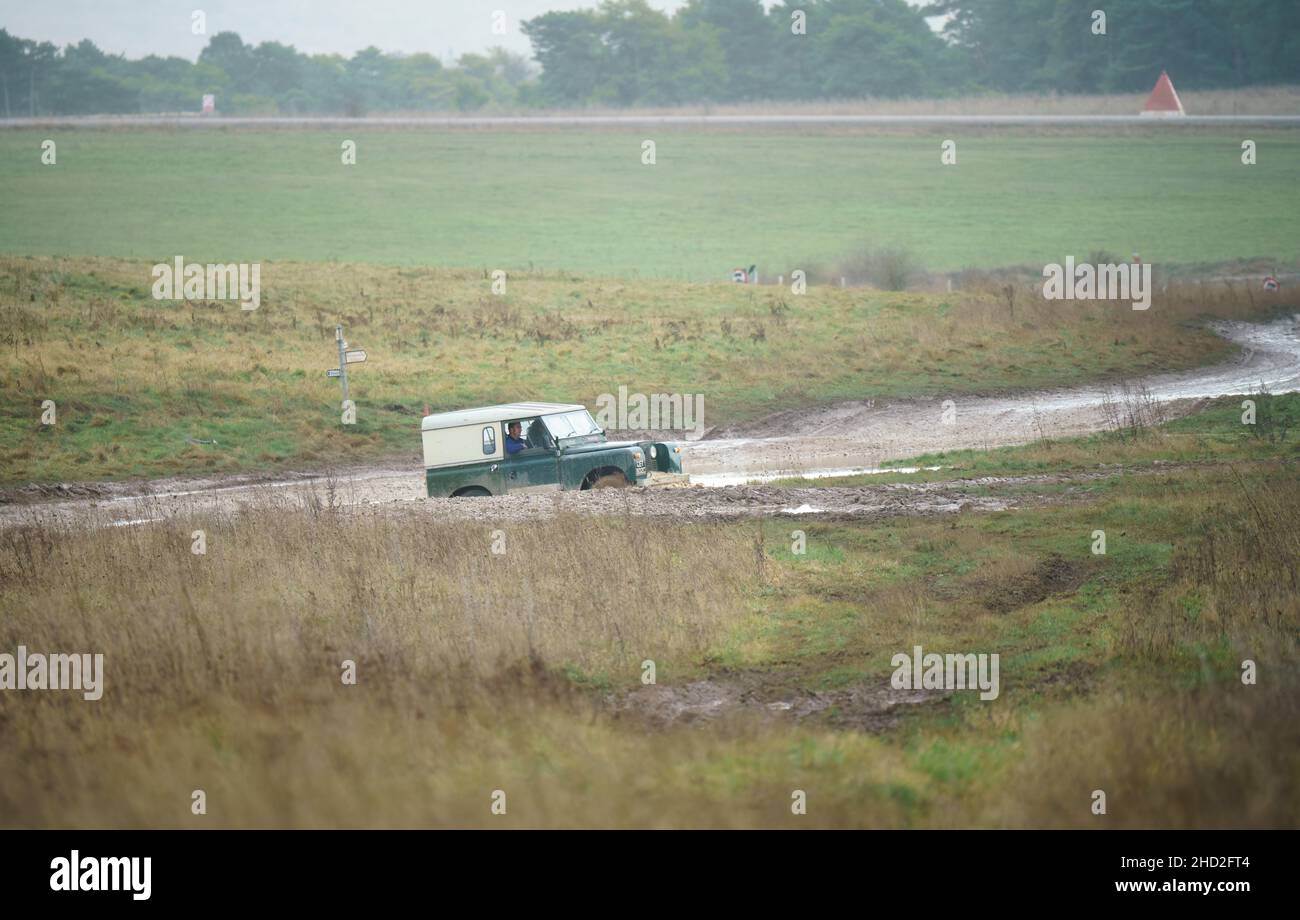 a vintage Land Rover series 2 vehicle driving off-road through deep ...