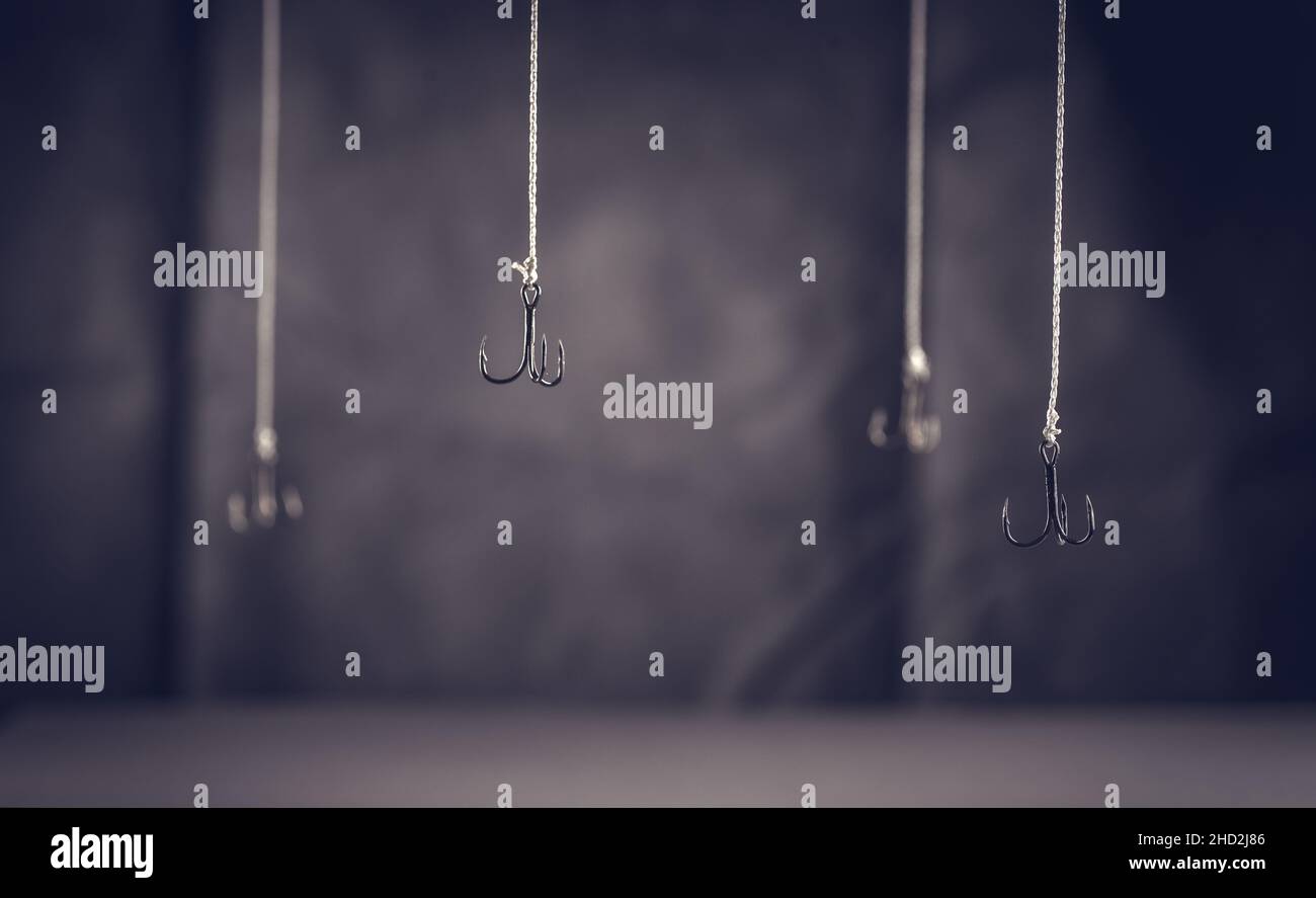 Fishing hooks hang on a dark background. Get hooked. Fall into the trap ...