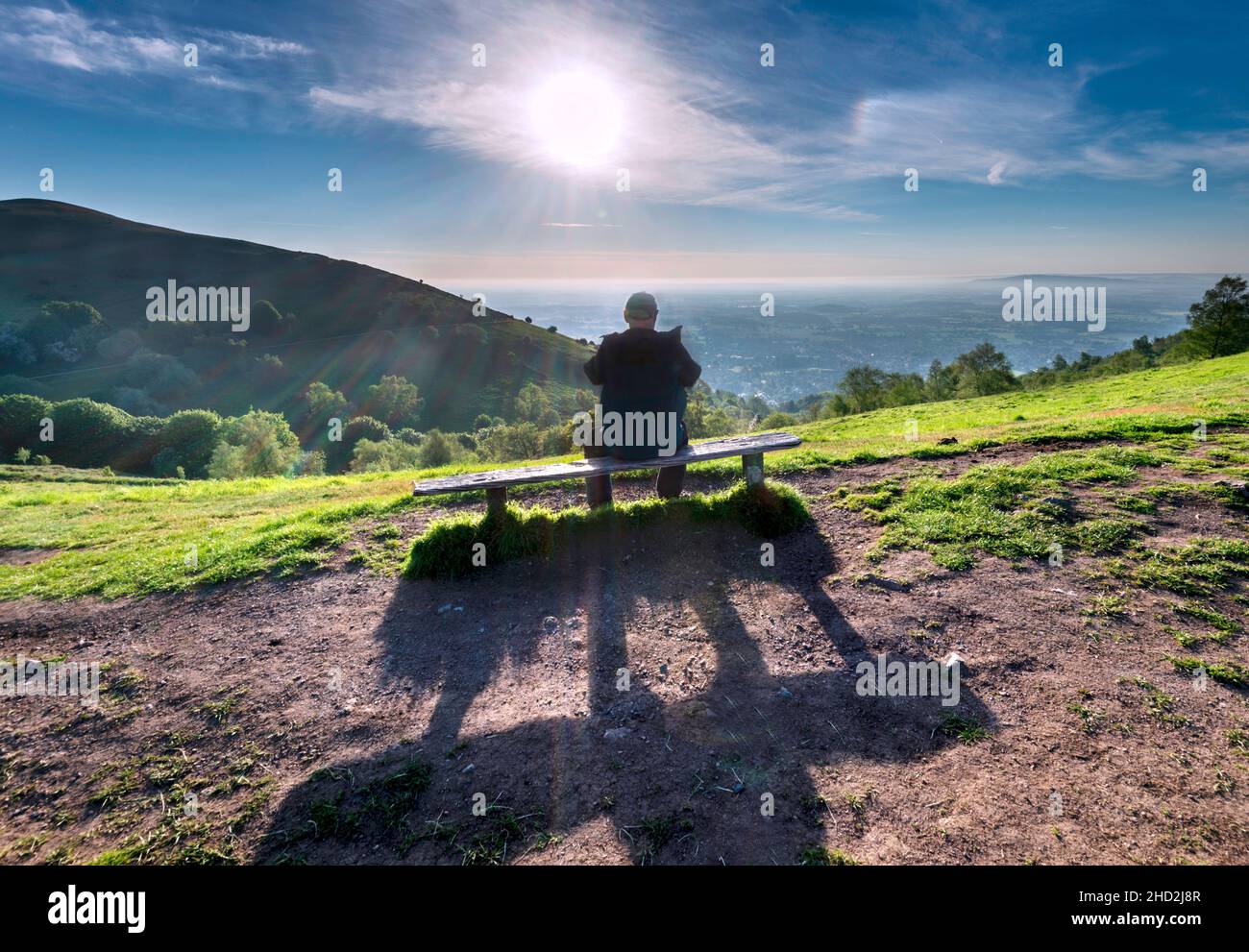 A distant human figure,sitting on a wooden bench in watching in awe the ...