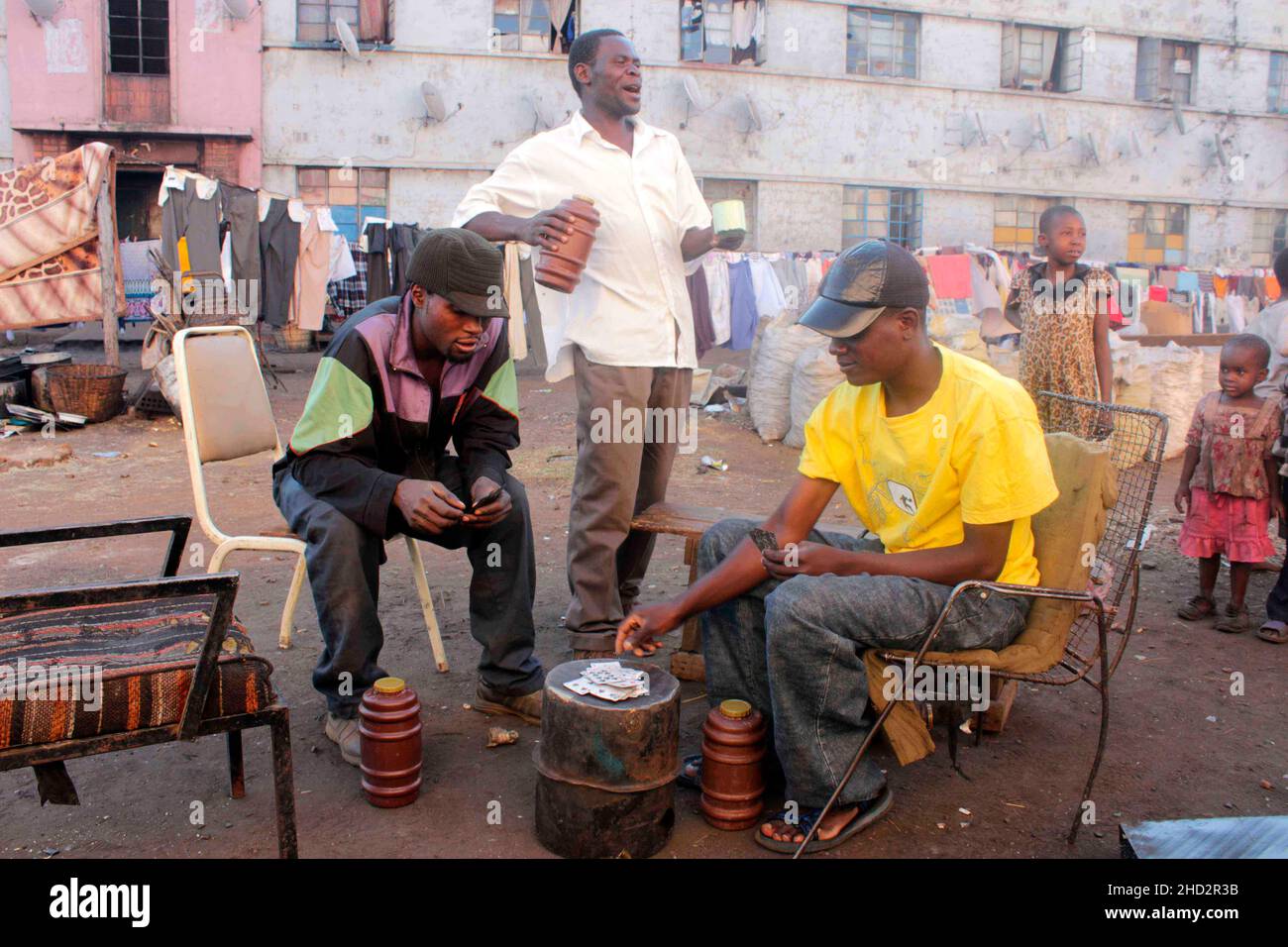 Men are seen playing cards at sunset whilst drinking opaque beer ...