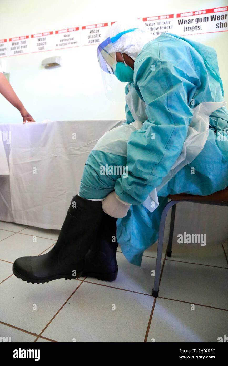 A nurse dons a pair of boots to demonstrate how health personnel ...