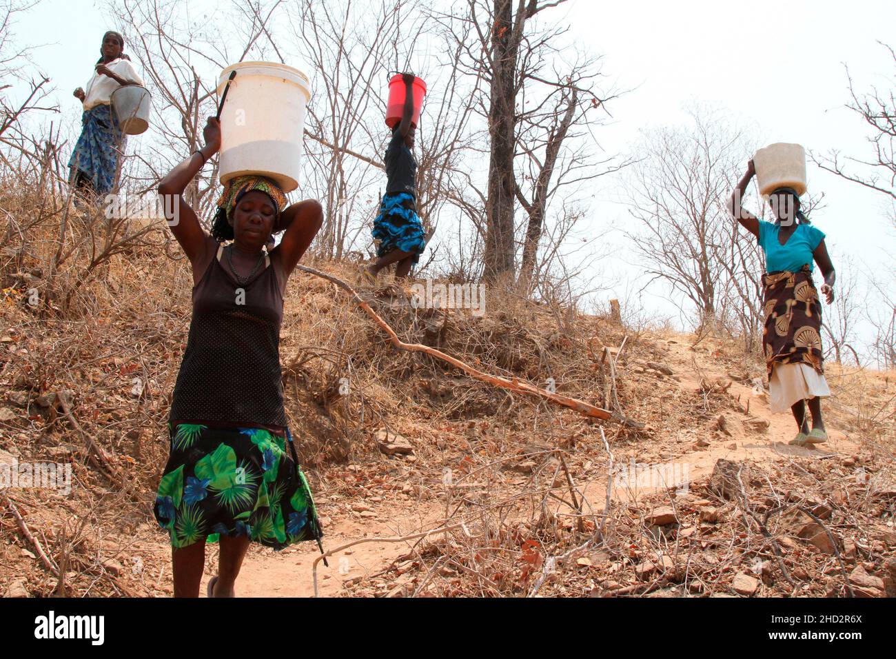 Women are seen coming down a slope carrying buckets of sand to help in ...