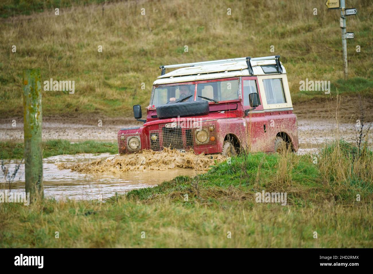 a vintage Land Rover series 2 vehicle driving off-road through deep ...