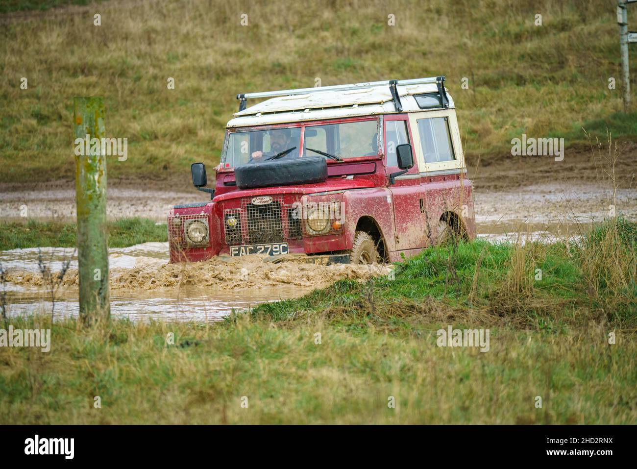 a vintage Land Rover series 2 vehicle driving off-road through deep ...