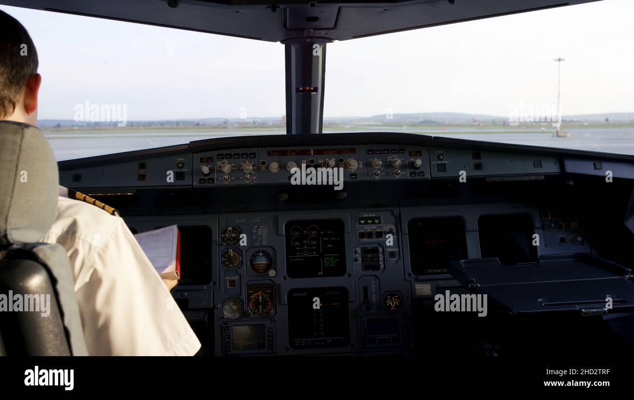 Rear view of pilot operating controls of corporate jet. Captain in the ...