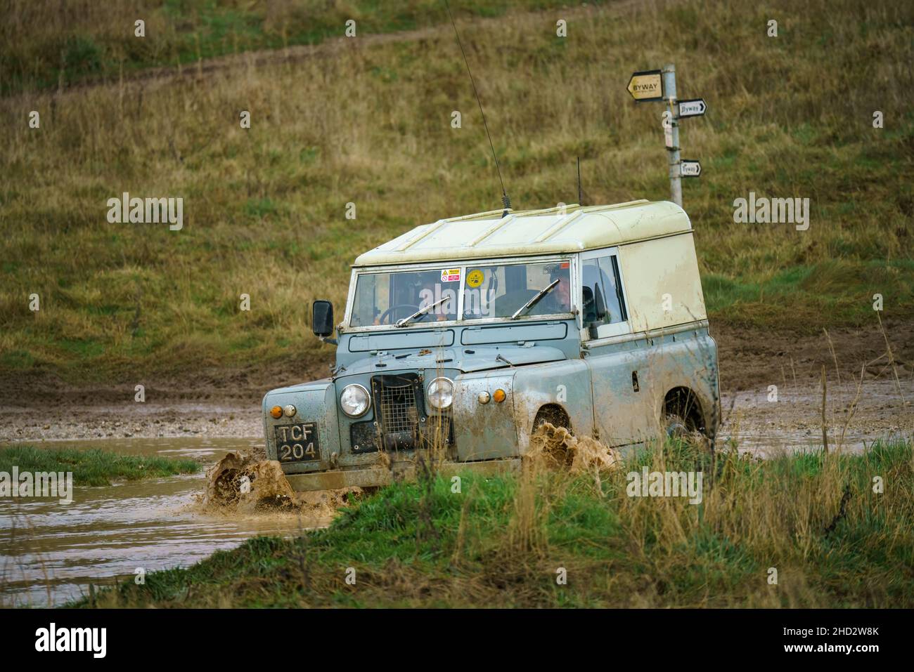 a vintage Land Rover series 2 vehicle driving off-road through deep ...