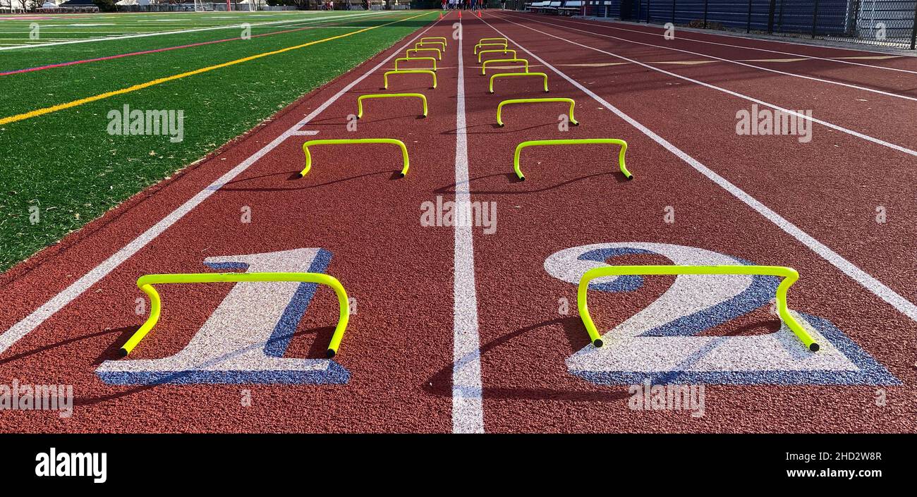 Lanes 1 and 2 of a red track is set up with small mini yellow hurdles ...