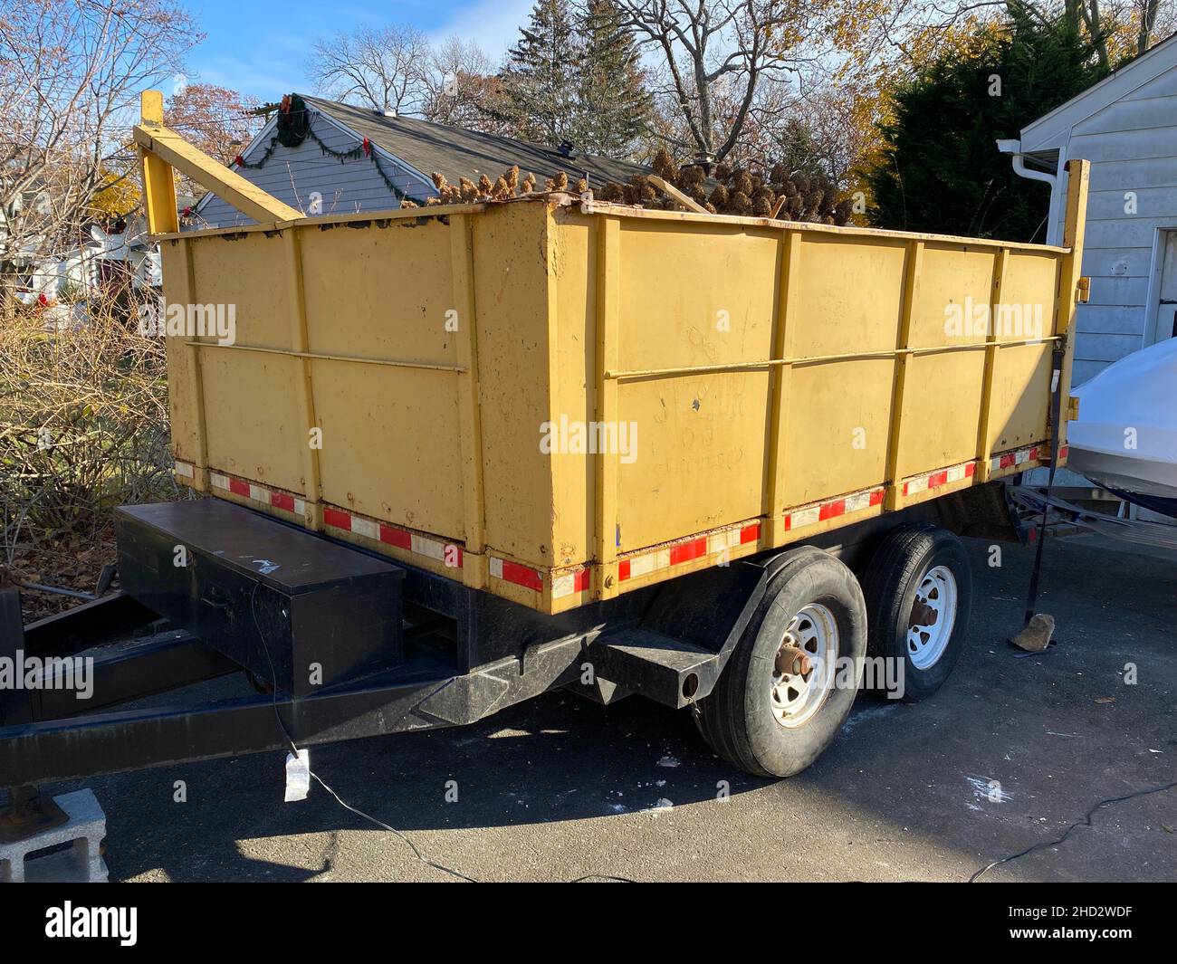A portable rubbish yellow dumpster on a trailer in a residential homes ...