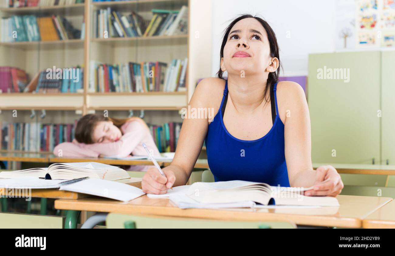 Young girl is thinking about difficult task at the desk Stock Photo - Alamy