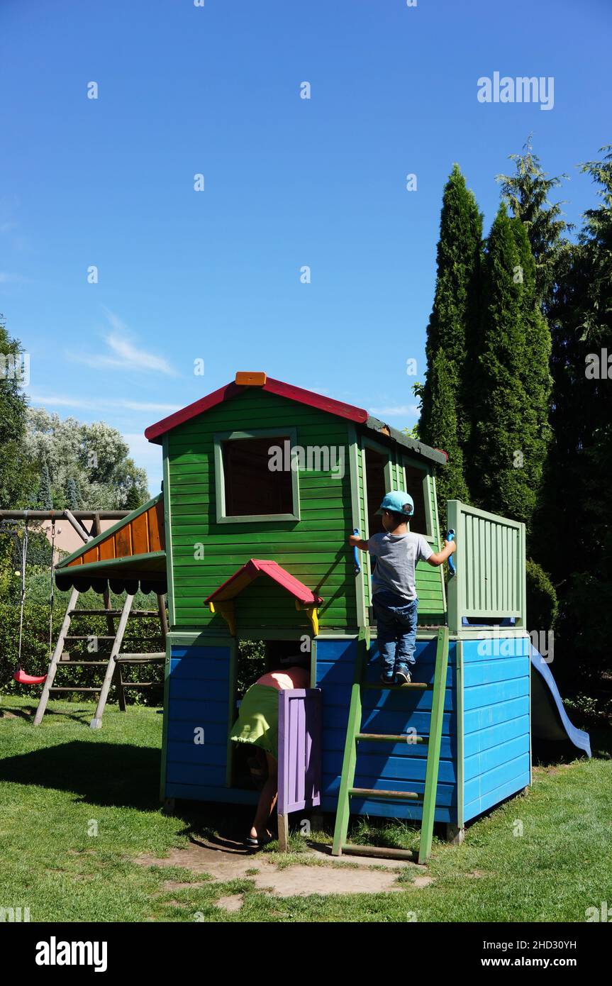 Children playing by a wooden green hut of a playground in thHortulus ...