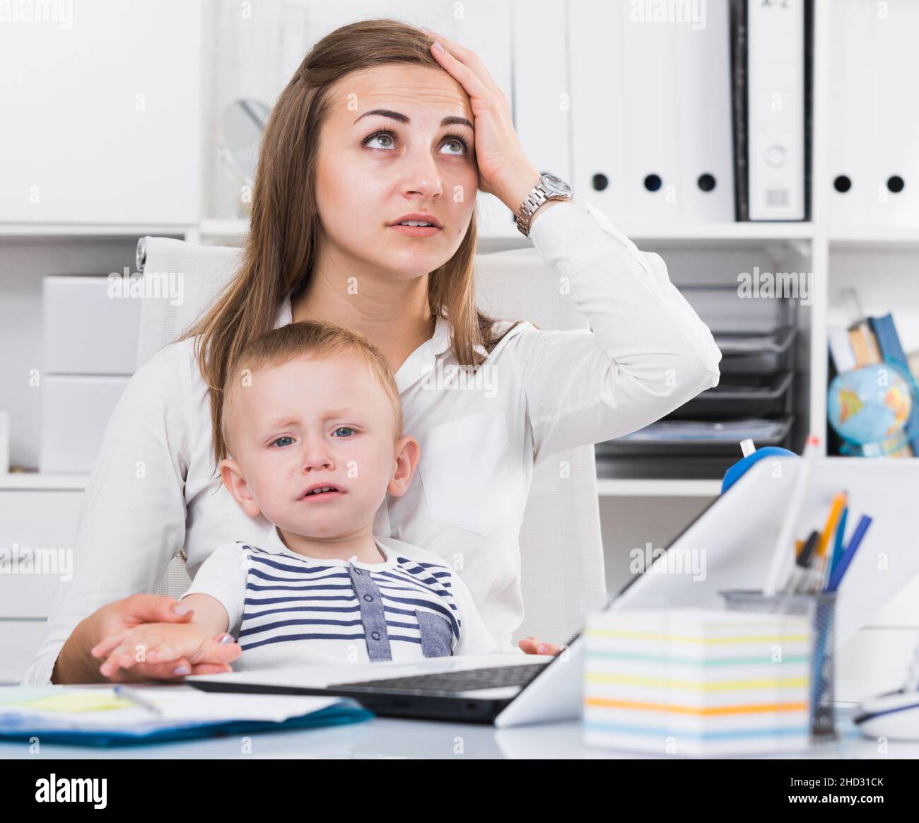 Perplexed woman with kid is having problems while working Stock Photo ...