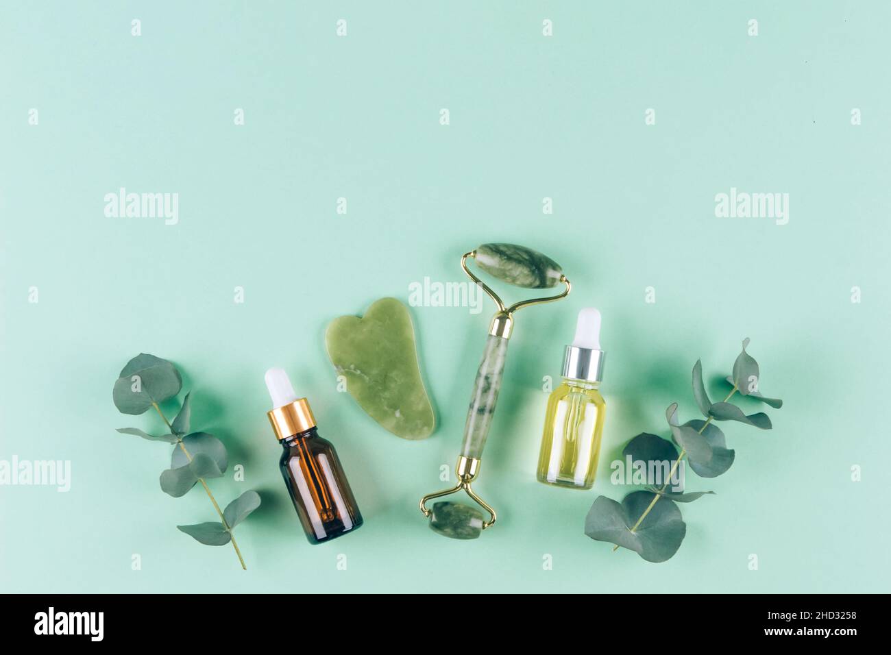 Flat lay composition with jade gua sha facial roller with beauty serum ...