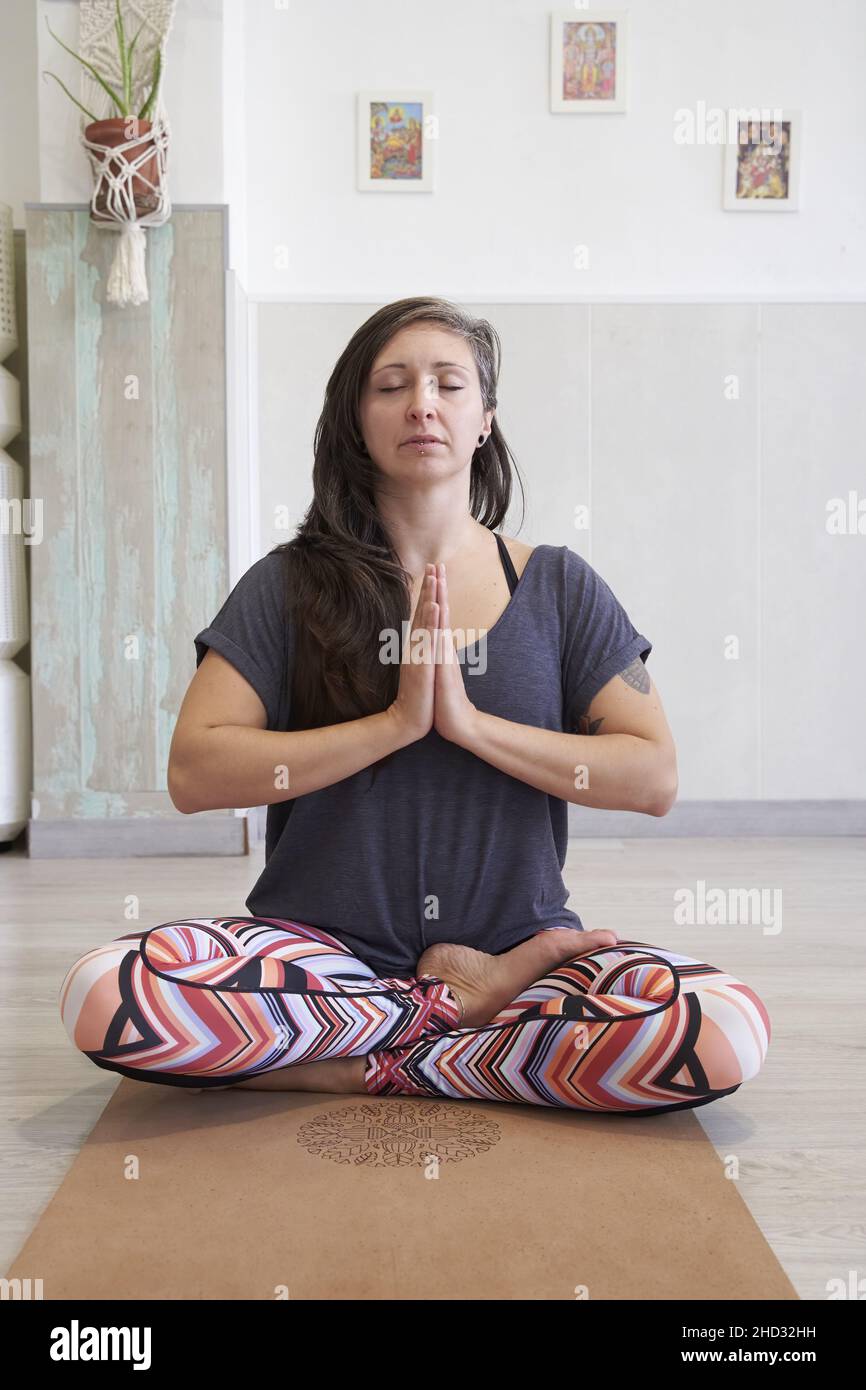 Young attractive sporty woman practicing yoga, doing Ardha Padmasana ...