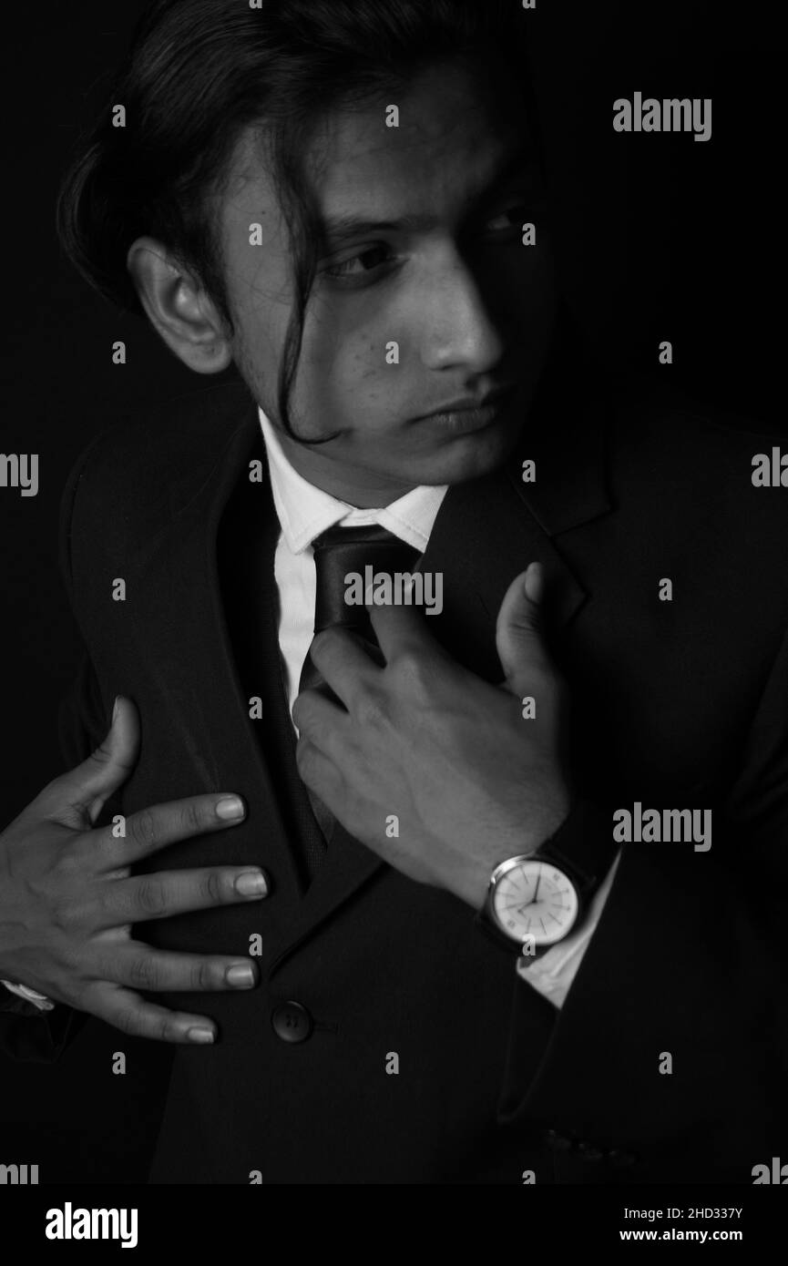 Vertical grayscale shot of an Indian man wearing a classy suit and ...