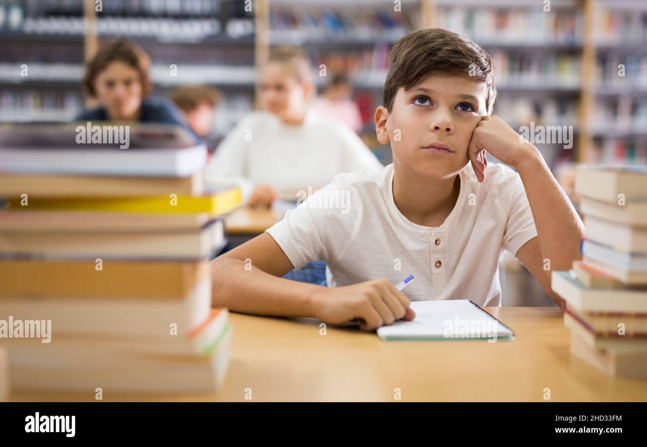 Bored young boy in library Stock Photo - Alamy