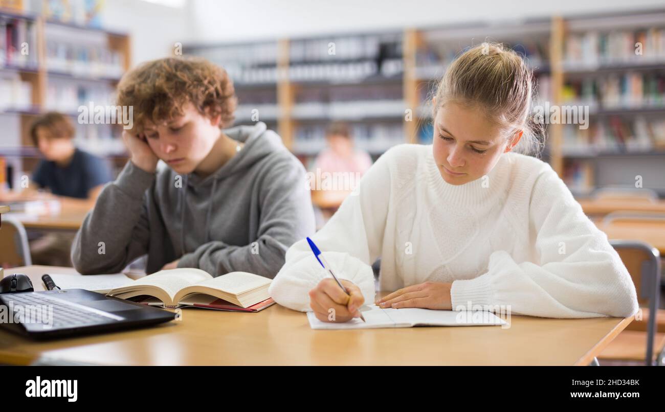 Girl and boy preparing for exams in library Stock Photo - Alamy