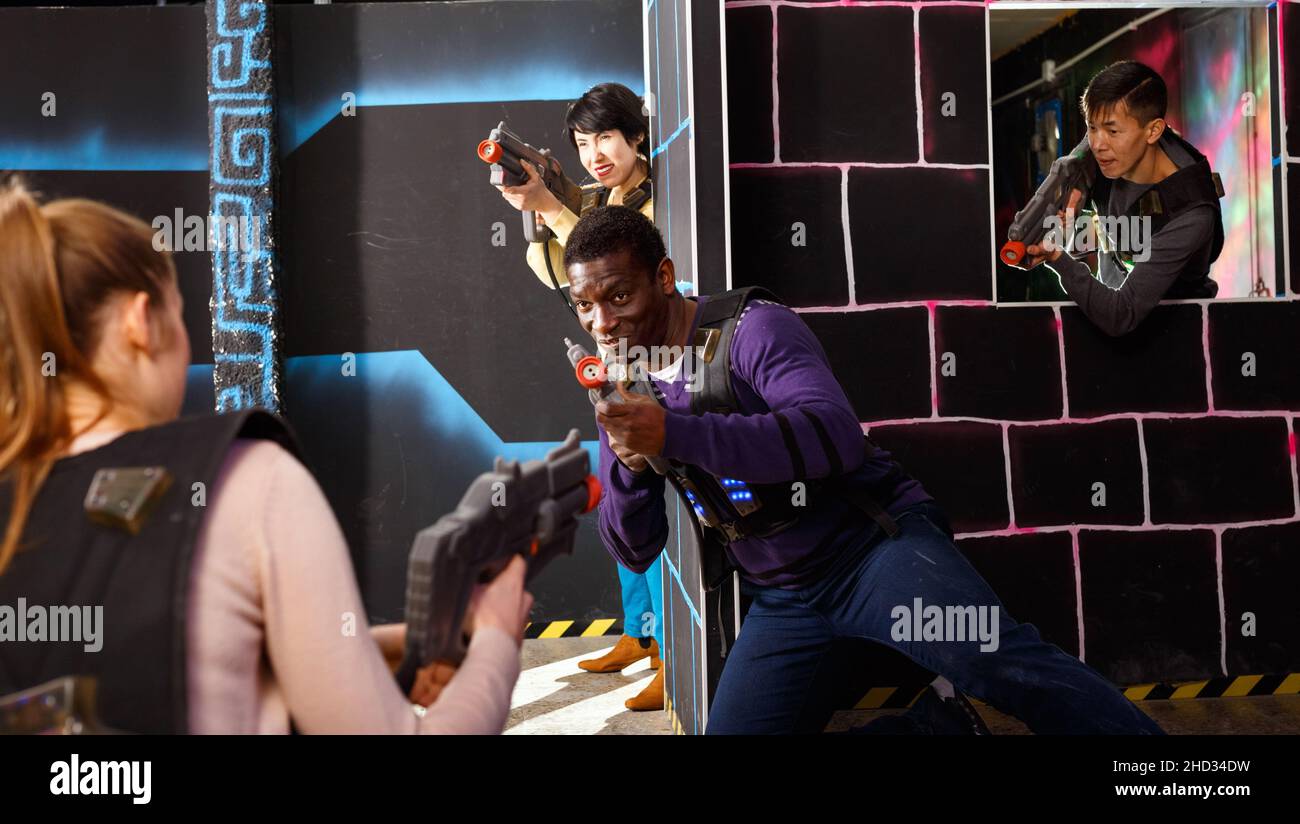 Modern people of different nationalities with laser pistols playing ...