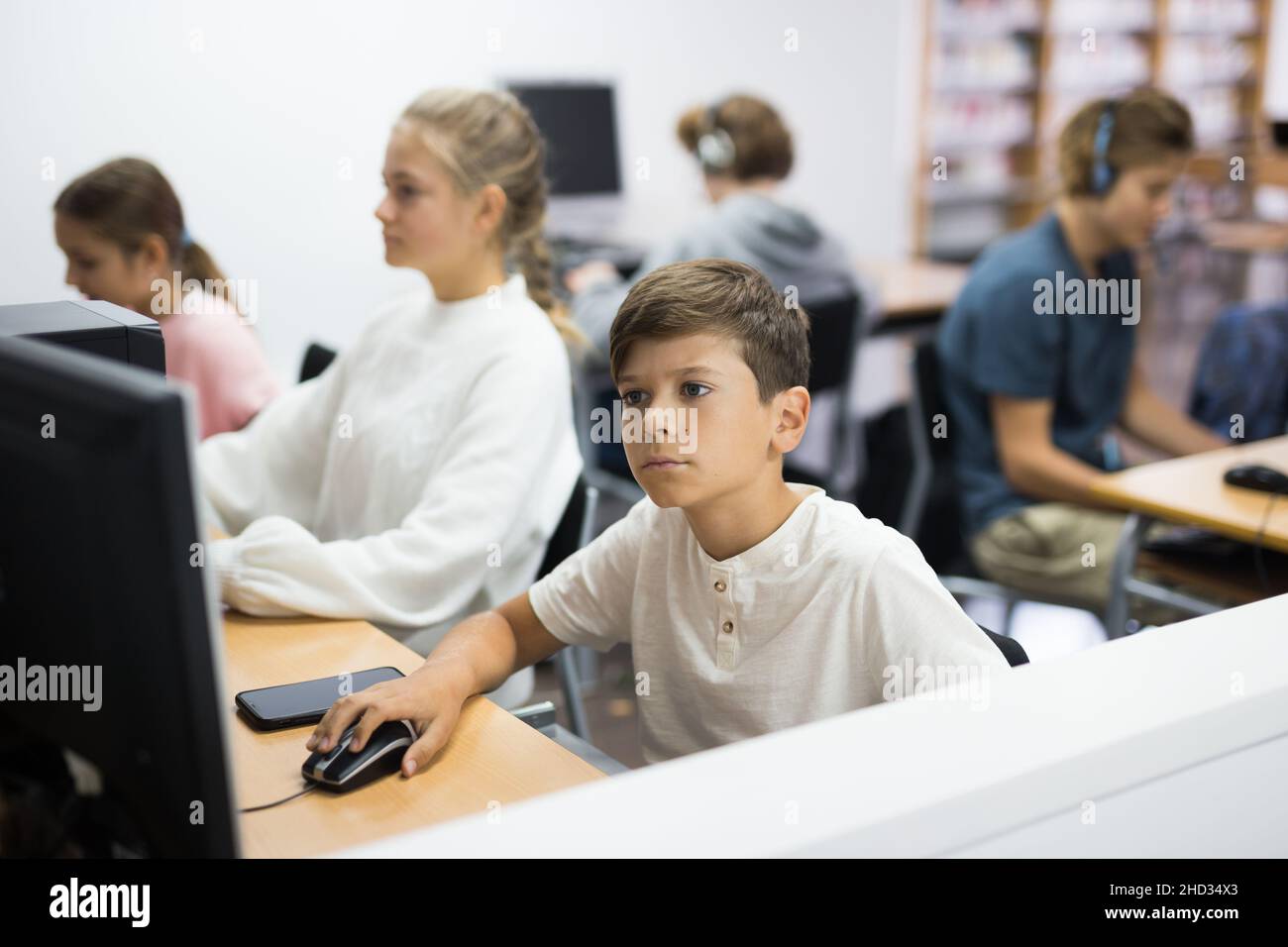Preteen boy and girl learn to solve problems on computer in school ...