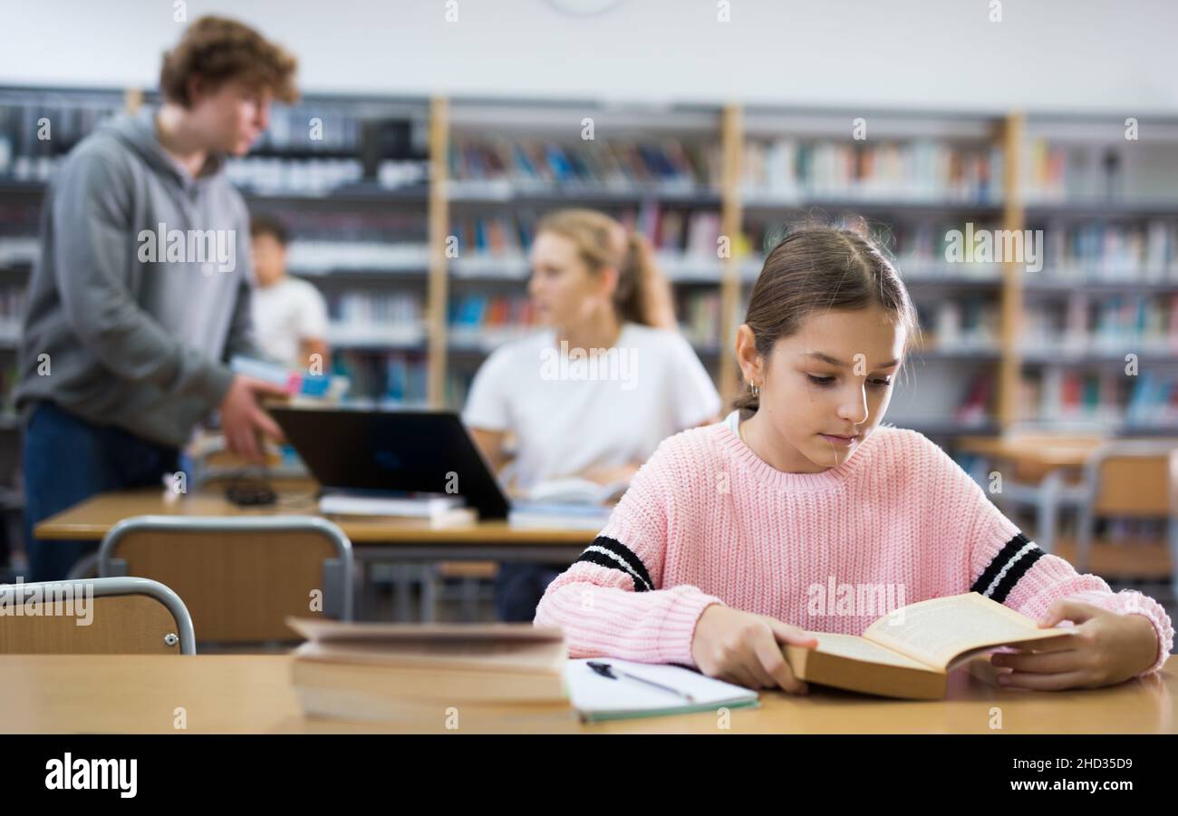 Young girl doing homework in library Stock Photo - Alamy