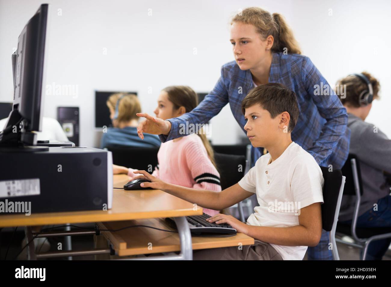 Teacher helping student with computer work Stock Photo - Alamy