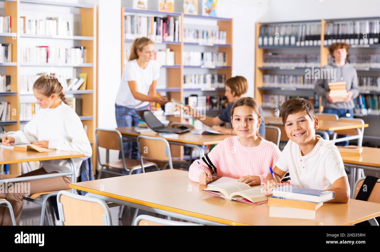 School friends spending time together in library, reading books Stock ...