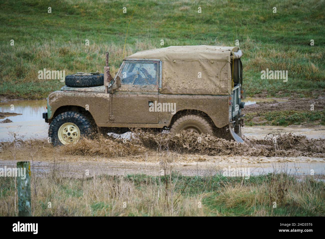 a Land Rover vehicle driving off-road through deep muddy water ...