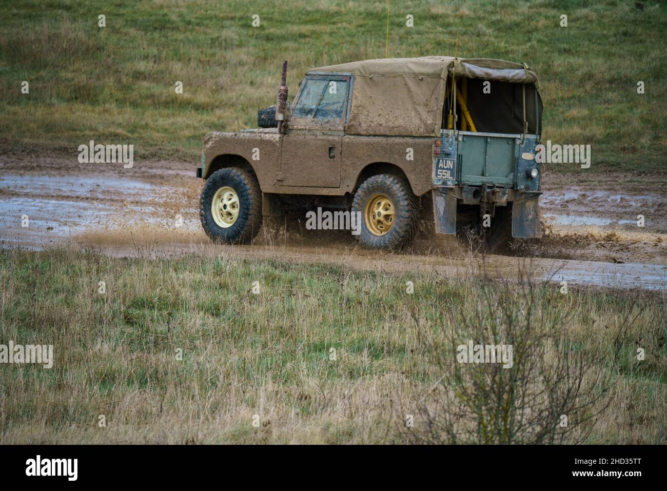 a Land Rover vehicle driving off-road through deep muddy water ...
