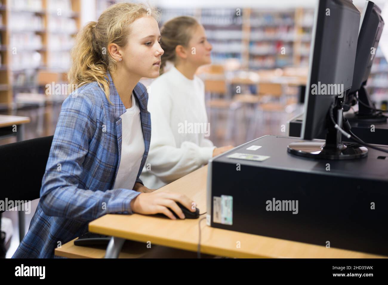 Teenager girls using computers in library Stock Photo - Alamy