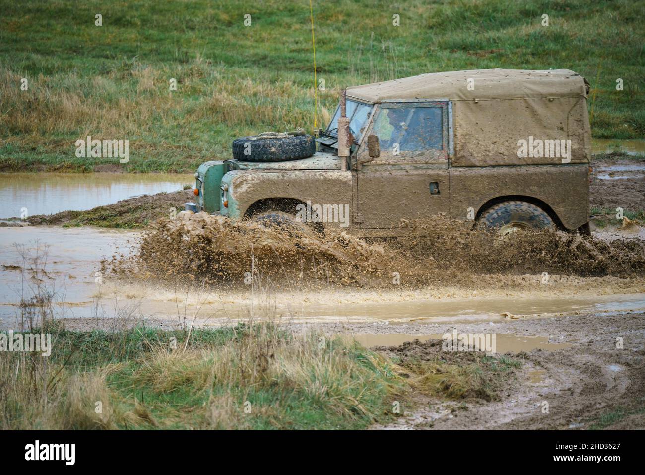 a Land Rover vehicle driving off-road through deep muddy water ...