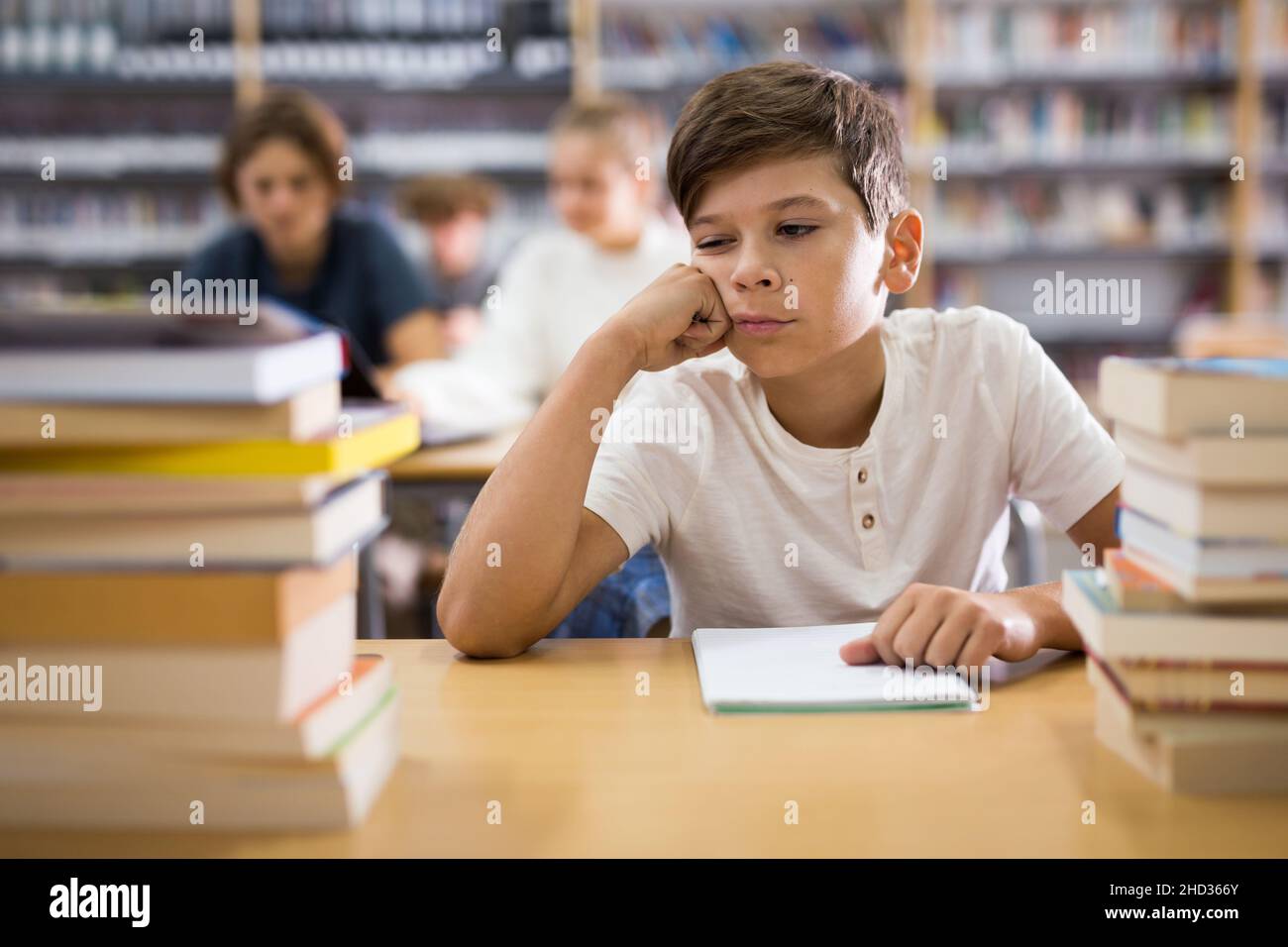 Bored teenage boy trying to prepare for exam in library Stock Photo - Alamy