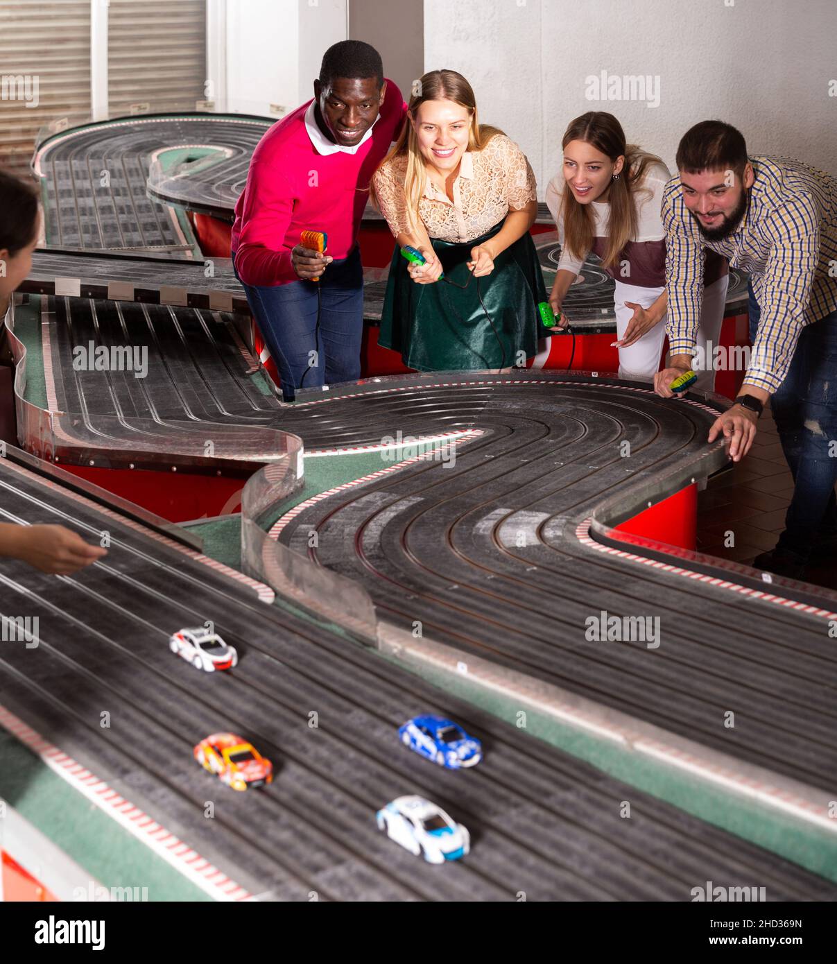 Happy friends play together with slot car racing Stock Photo - Alamy