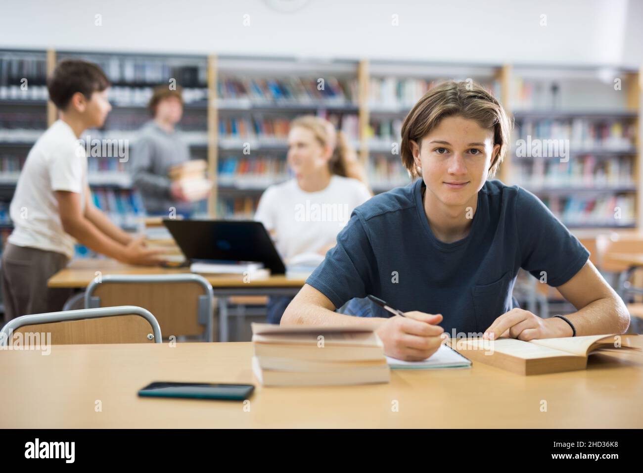 Teenager engaged in research working with books in library Stock Photo ...