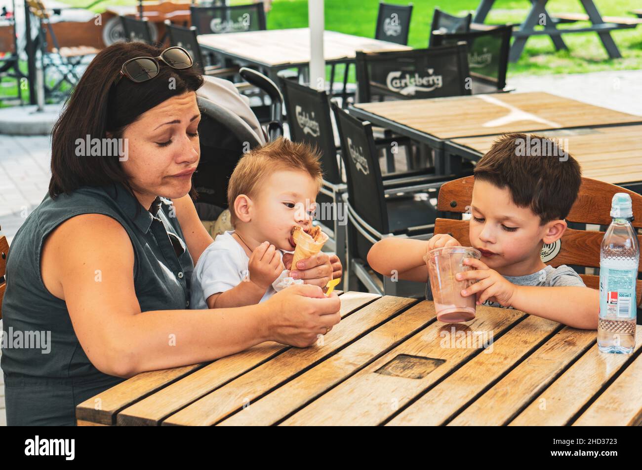Woman and two children eating ice cream by a table of a bar Stock Photo ...