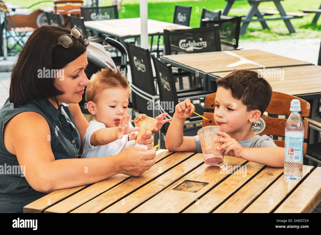 Woman and two children eating ice cream by a table of a bar Stock Photo ...