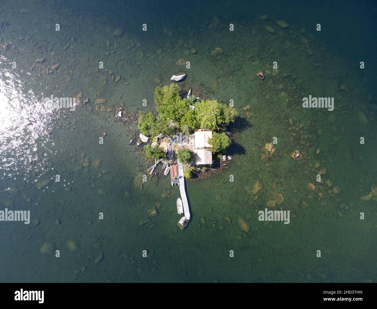 N aerial view of a small rock island with a tree growing from it in the ...