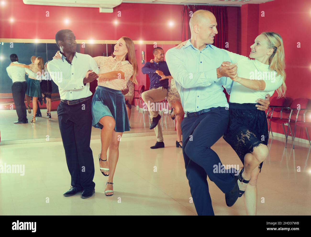 Young positive people dancing vigorous jive movements in dance studio ...