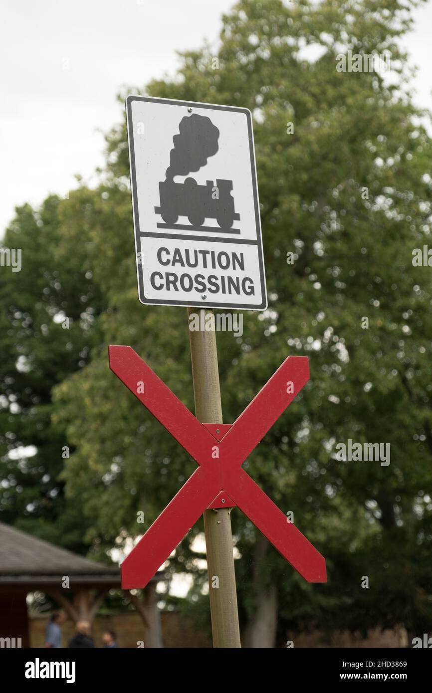 Vertical shot of a "Caution Crossing" sign above a large red cross on ...