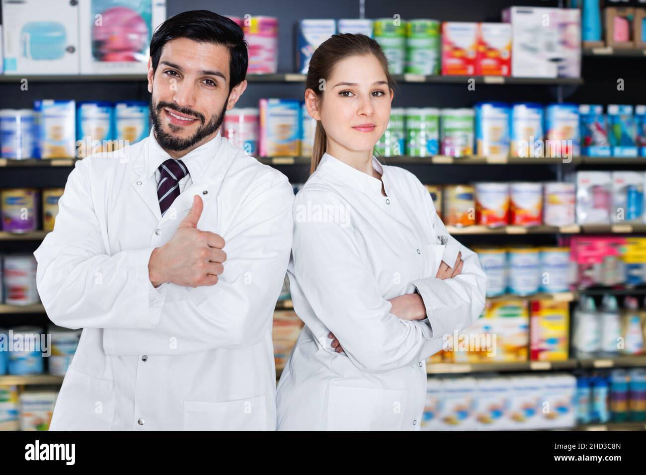 Portrait of two specialistes who are standing near shelves with ...