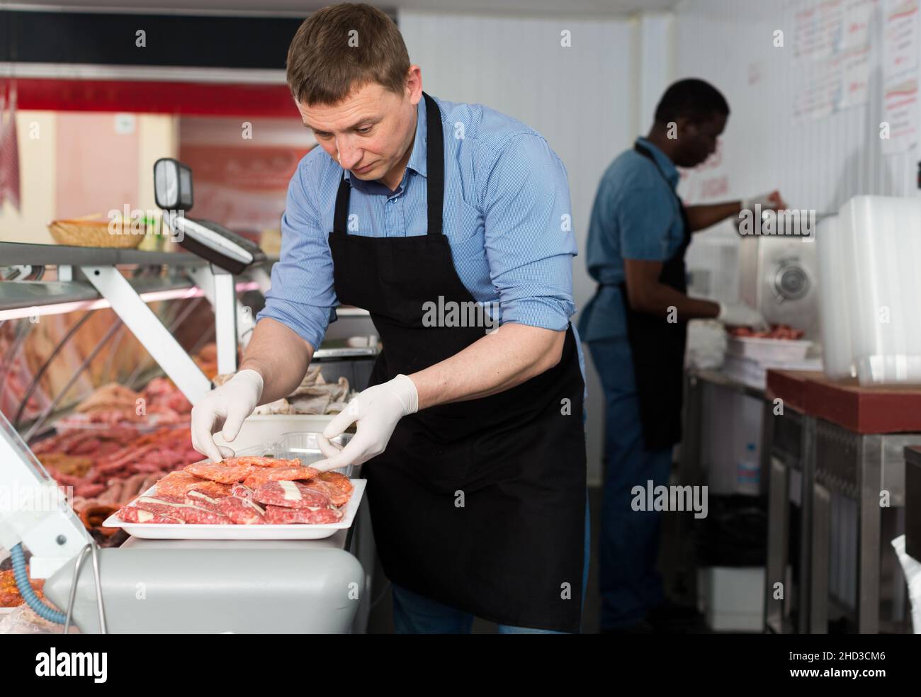 Butchers working behind counter Stock Photo - Alamy
