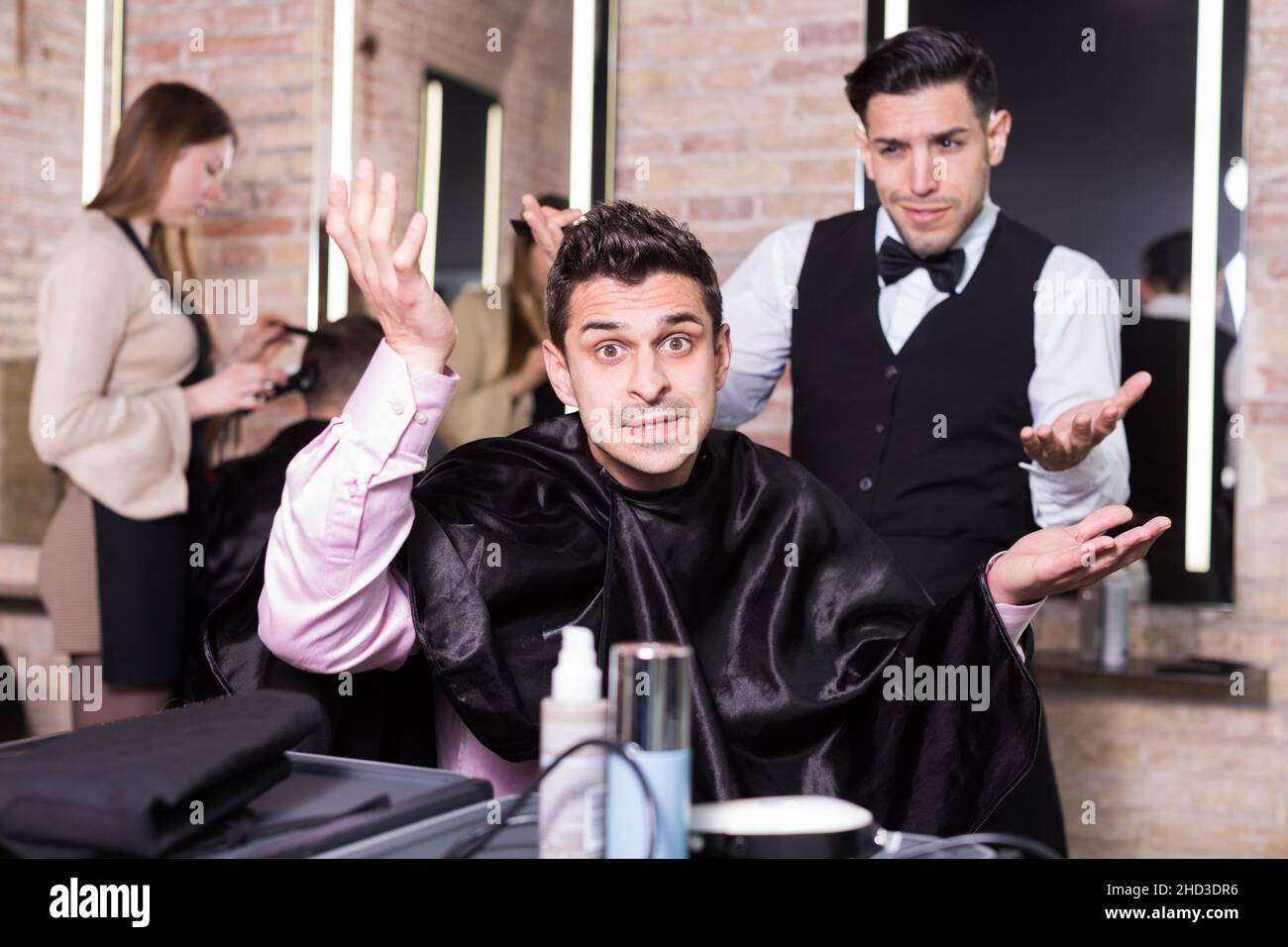 Shocked man with apologetic male hairstylist Stock Photo - Alamy